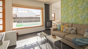 Uma sala de estar moderna com uma janela ampla, lareira, sofá e área de jantar.