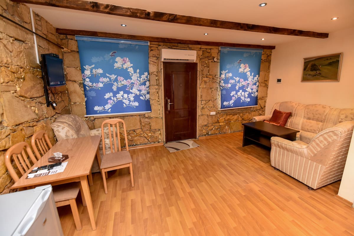Uma sala de estar acolhedora, com parede de pedra, móveis de madeira e arte floral.