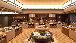 Um restaurante moderno com uma estação central de fondue, vários balcões de serviço e cozinheiros uniformizados.