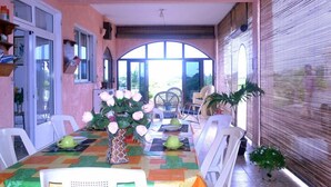 Uma área de refeições com uma mesa posta para quatro pessoas, cercada por cadeiras brancas.