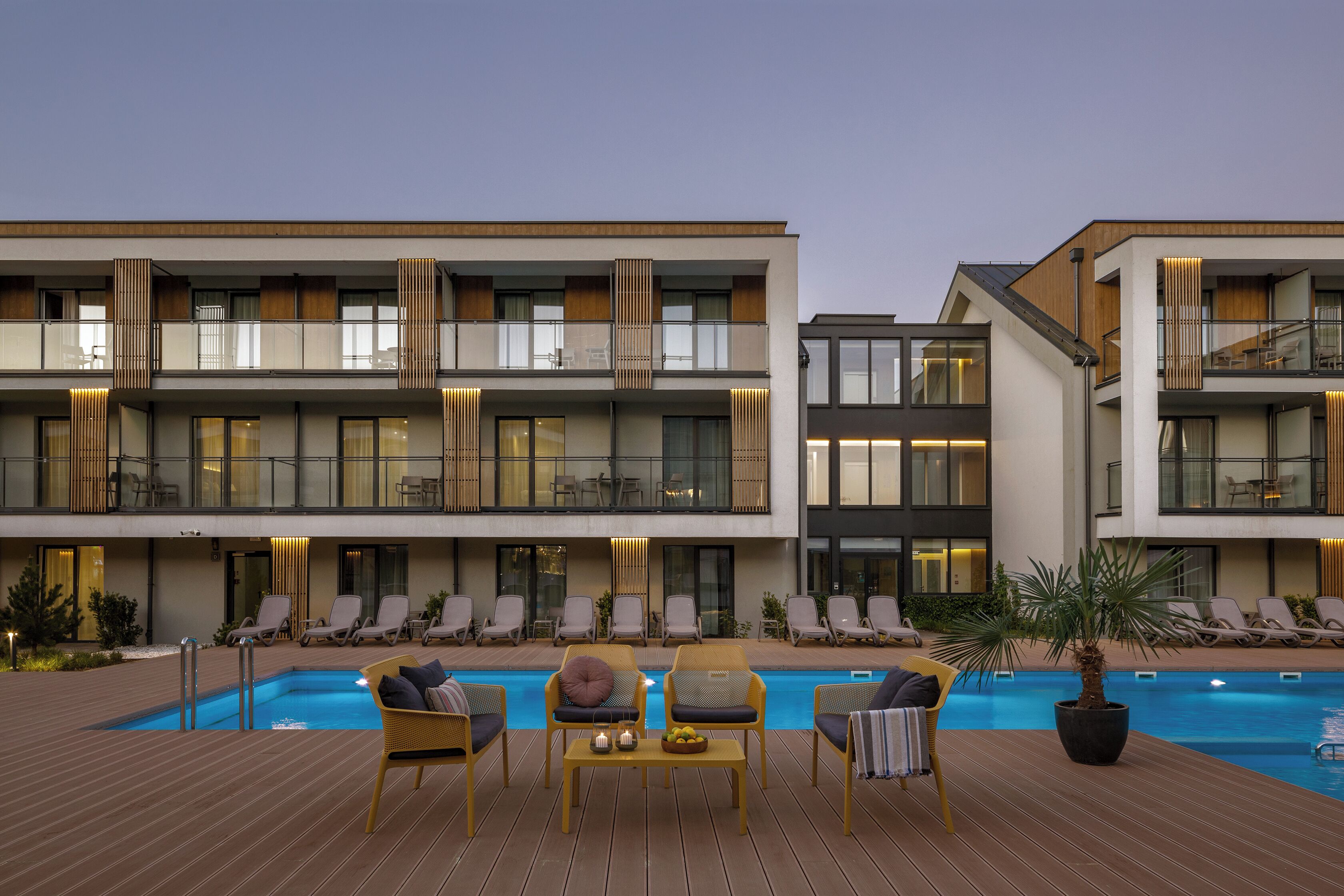 Um hotel moderno com área de piscina, várias varandas e cadeiras de lounge.