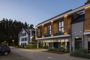 Um edifício moderno com área de recepção, grandes janelas e estacionamento.