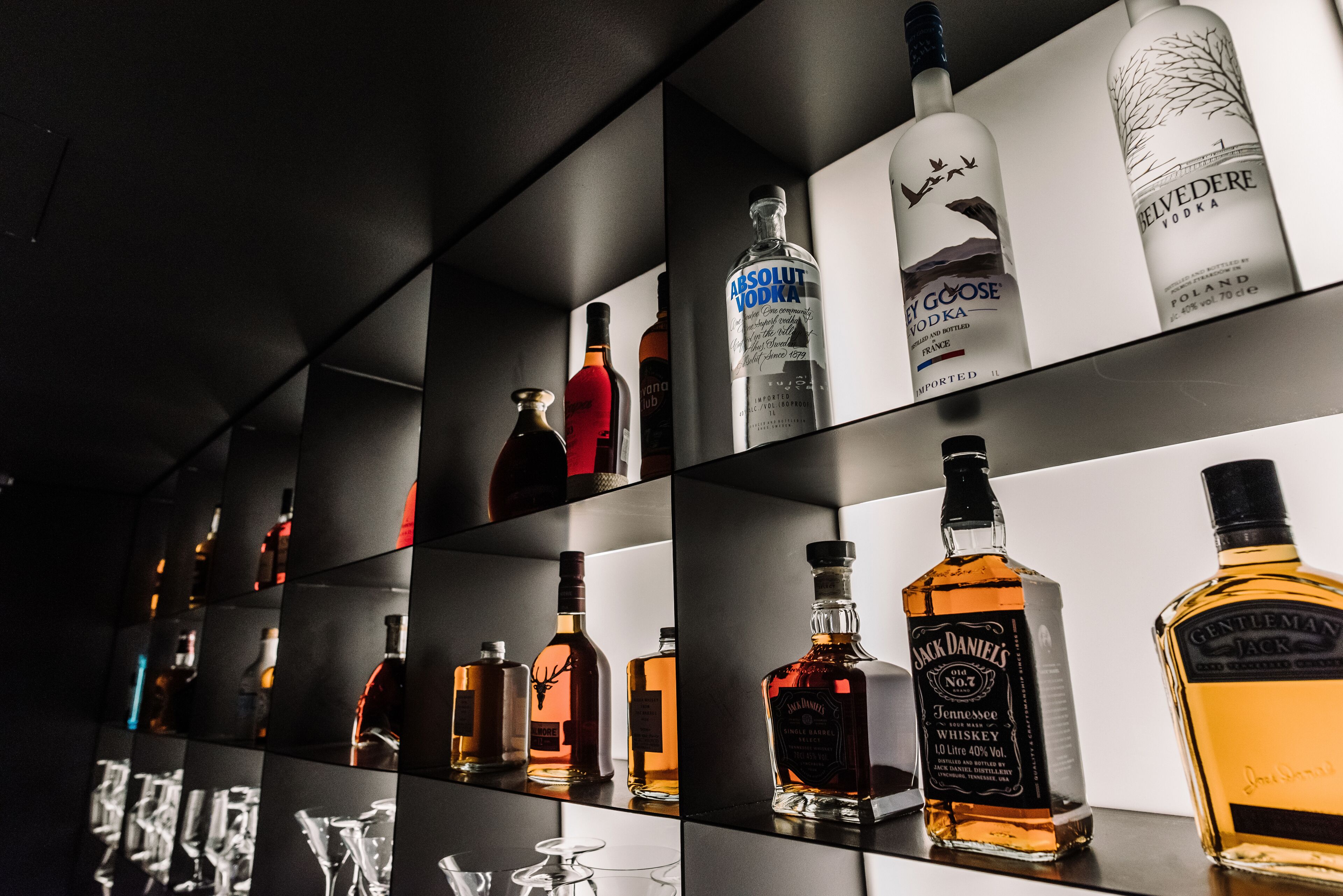 Uma área de bar com diversas garrafas de bebidas alcoólicas expostas em prateleiras.