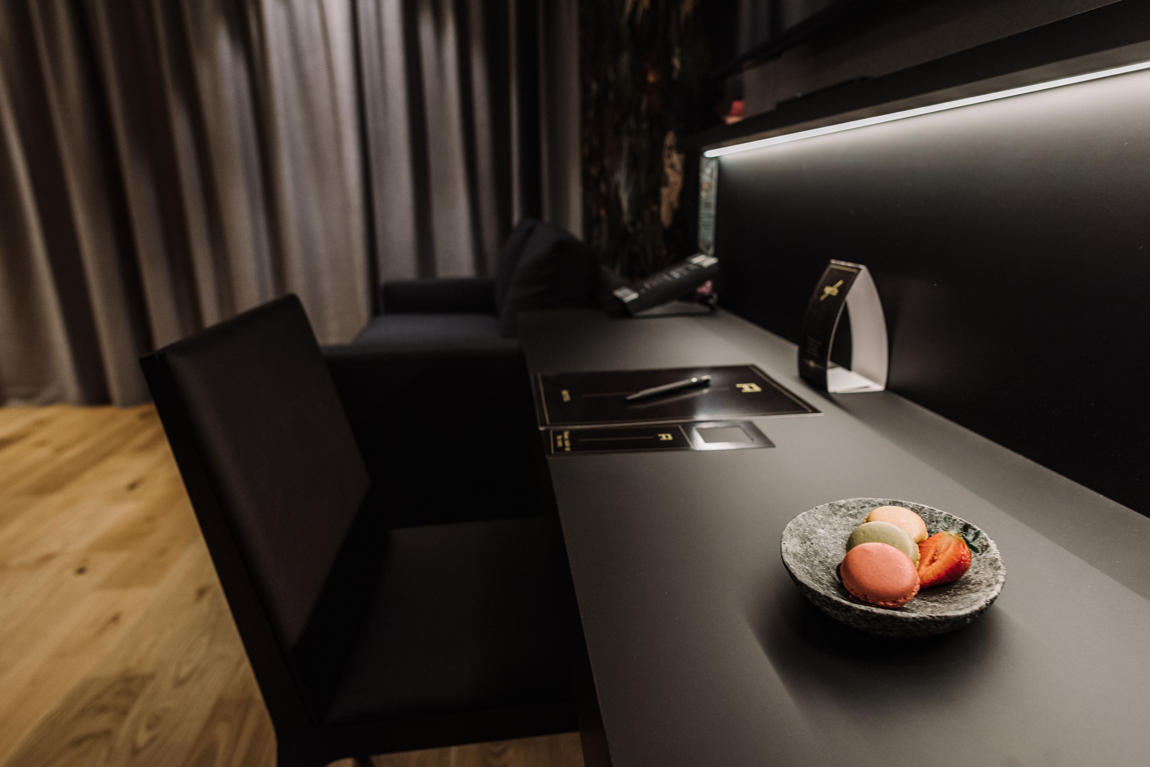 Um espaço de bar moderno com um balcão elegante, uma taça de macarons e um laptop.