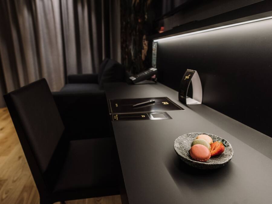 Um espaço de bar moderno com um balcão elegante, uma taça de macarons e um laptop.