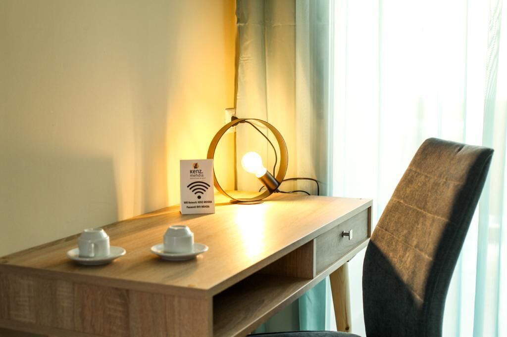 Uma mesa de madeira com um laptop, um sinal indicando acesso à internet Wi-Fi e uma luminária.