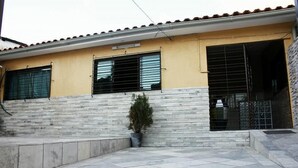 Um edifício com fachada amarela, um pátio com azulejos e um vaso de planta.
