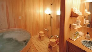 Uma casa de banho de madeira com hidromassagem, sanita, chuveiro e lavatório com artigos de higiene pessoal.