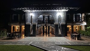 Uma entrada imponente com arco de pedra, várias escadarias e áreas de estar ao ar livre.