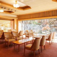 Quarto de hotel com uma janela ampla, móveis de madeira e vista para um jardim.