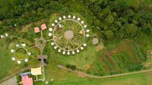 Vista aérea de um parque com canteiros de flores circulares, um jardim circular central e caminhos ao redor.