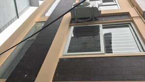 Um edifício com várias andares, fachada bege, janelas grandes com persianas e aparelhos de ar condicionado na parte externa.
