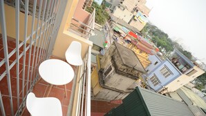 Vista de uma varanda com vista para uma rua com prédios, uma bandeira e uma motocicleta estacionada.