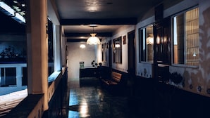 Um corredor com um banco, uma luminária pendente e uma janela com vista para o exterior.