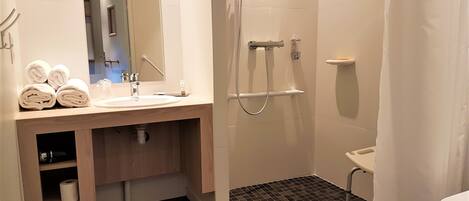 Uma casa de banho moderna com lavatório, espelho, porta-toalhas, chuveiro e sanita.