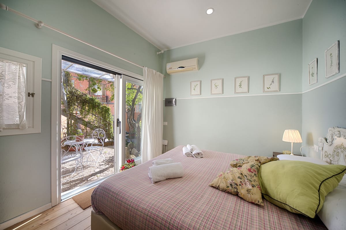 Quarto com cama, janela e vista para área externa.