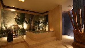 Uma casa de banho moderna com uma banheira grande, um compartimento de vidro com plantas tropicais e uma composição de bambu.