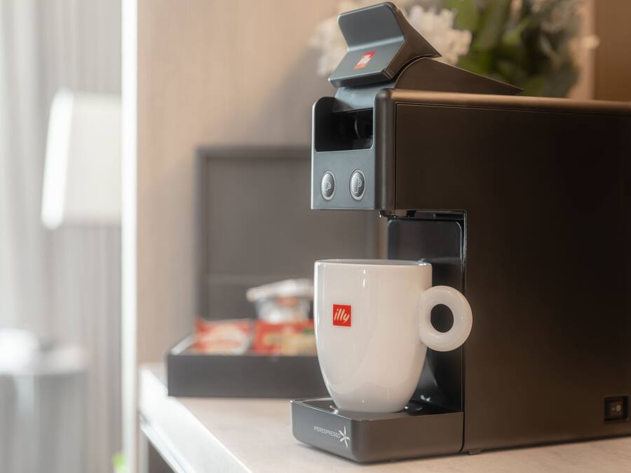 Máquina de café com porta-copos, painel de controle e logotipo da marca.