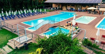 Uma área de piscina com várias piscinas, espreguiçadeiras e uma ponte.