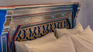 Cama com cabeceira decorativa com padrões elaborados e um travesseiro.