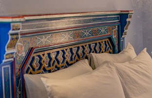 Cama com cabeceira decorativa com padrões elaborados e um travesseiro.