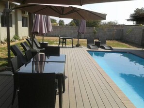 Uma área na piscina com deck de madeira, espreguiçadeiras e guarda-sóis.