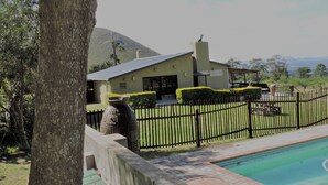 Um edifício com piscina, cercado por uma vedação e árvores.