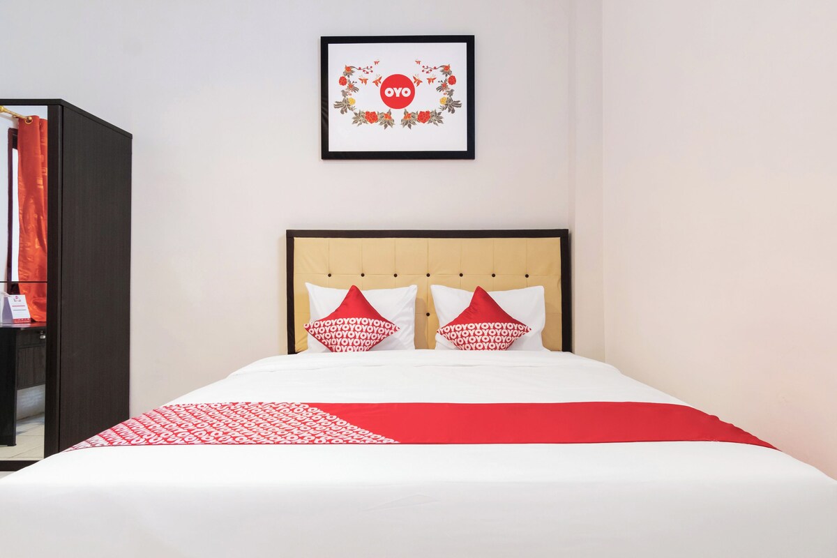 Quarto de hotel com cama, um quadro pendurado na parede e um guarda-roupa.