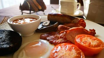 Prato de café da manhã com ovos, bacon, tomates, cogumelos e feijão.