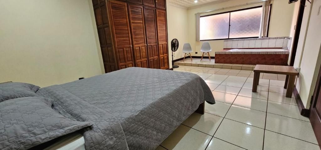 Quarto com cama, guarda-roupa de madeira, um banco e janela com vista.