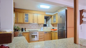 Cozinha com armários de madeira, eletrodomésticos de aço inoxidável e bancada de granito.