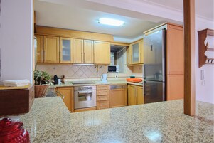 Cozinha com armários de madeira, eletrodomésticos de aço inoxidável e bancada de granito.