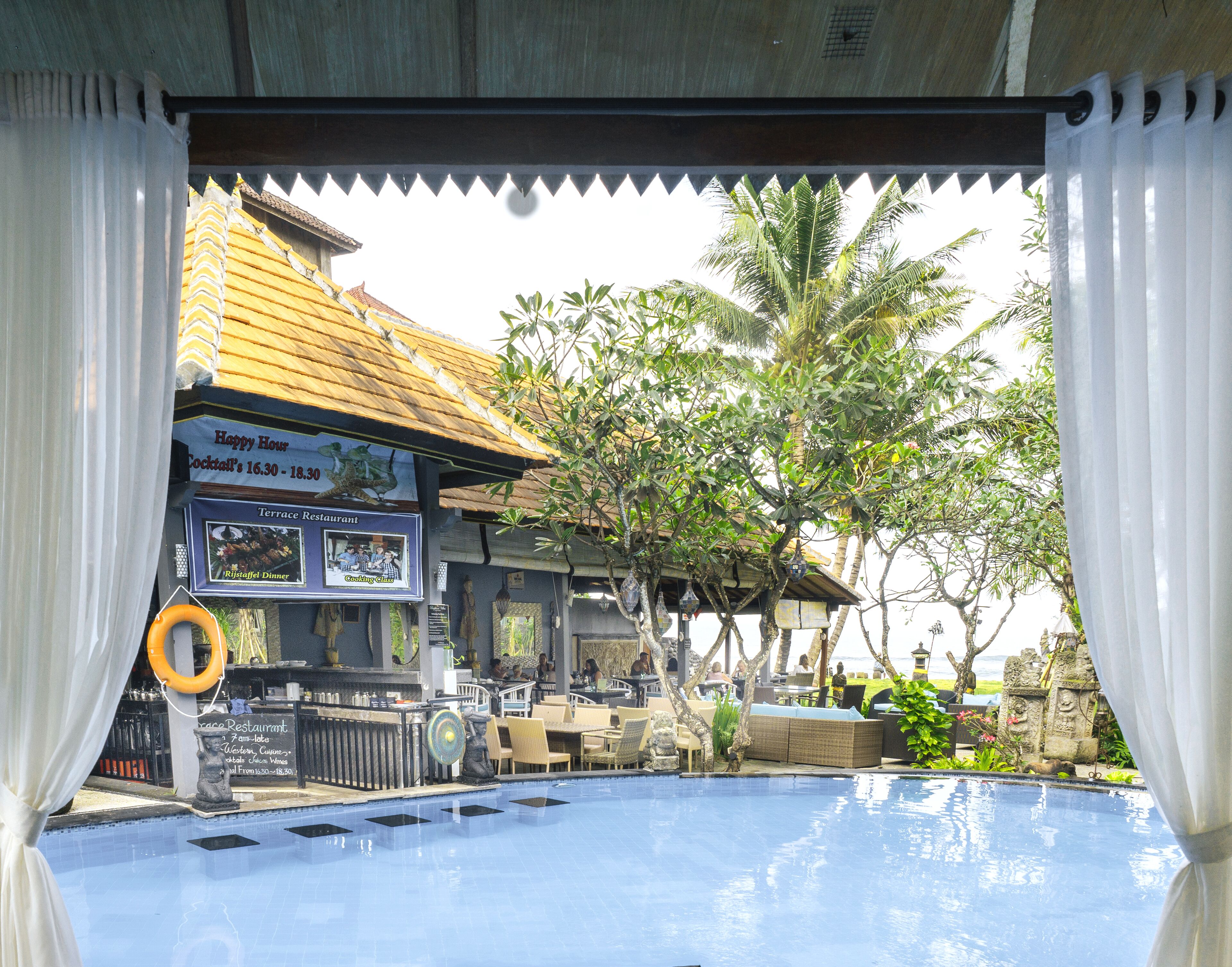 Uma área de piscina com restaurante no terraço, mesas ao ar livre e um flutuador.