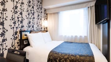 Quarto de hotel com cama, mesa de cabeceira, luminária, televisão e janela com cortinas.