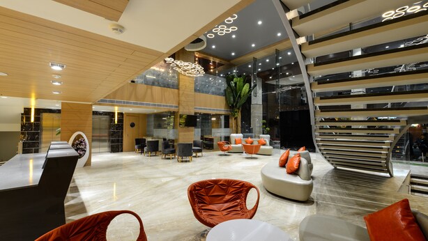 Um hall espaçoso com móveis modernos, um balcão de recepção e uma grande planta.