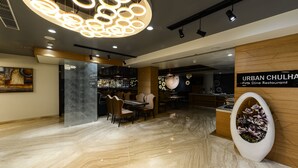 Interior de restaurante moderno com piso de mármore, luminária circular no teto e placa com a inscrição 'URBAN CHULHA Fine Dine Restaurant'.