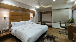 Quarto de hotel com uma cama grande, uma escrivaninha, uma cadeira e uma pequena mesa.