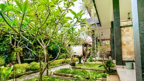 Um jardim bem cuidado, com diversas plantas e um caminho que leva a um edifício de fachada em pedra.