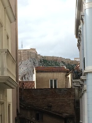 Uma rua estreita com edifícios em ambos os lados, um com varanda e outro com fachada de pedra.