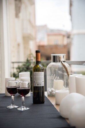 Uma mesa com uma garrafa de vinho, dois copos de vinho tinto, velas e um frasco decorativo.