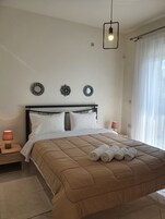 Cama bem arrumada com colcha marrom, duas luminárias de cabeceira e três objetos decorativos na parede.