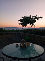 Uma mesa de vidro redonda com uma planta em vaso e um castiçal, com vista para o pôr do sol.