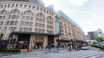 Um edifício grande com fachada clássica, entrada destacada e uma faixa de pedestres em frente.
