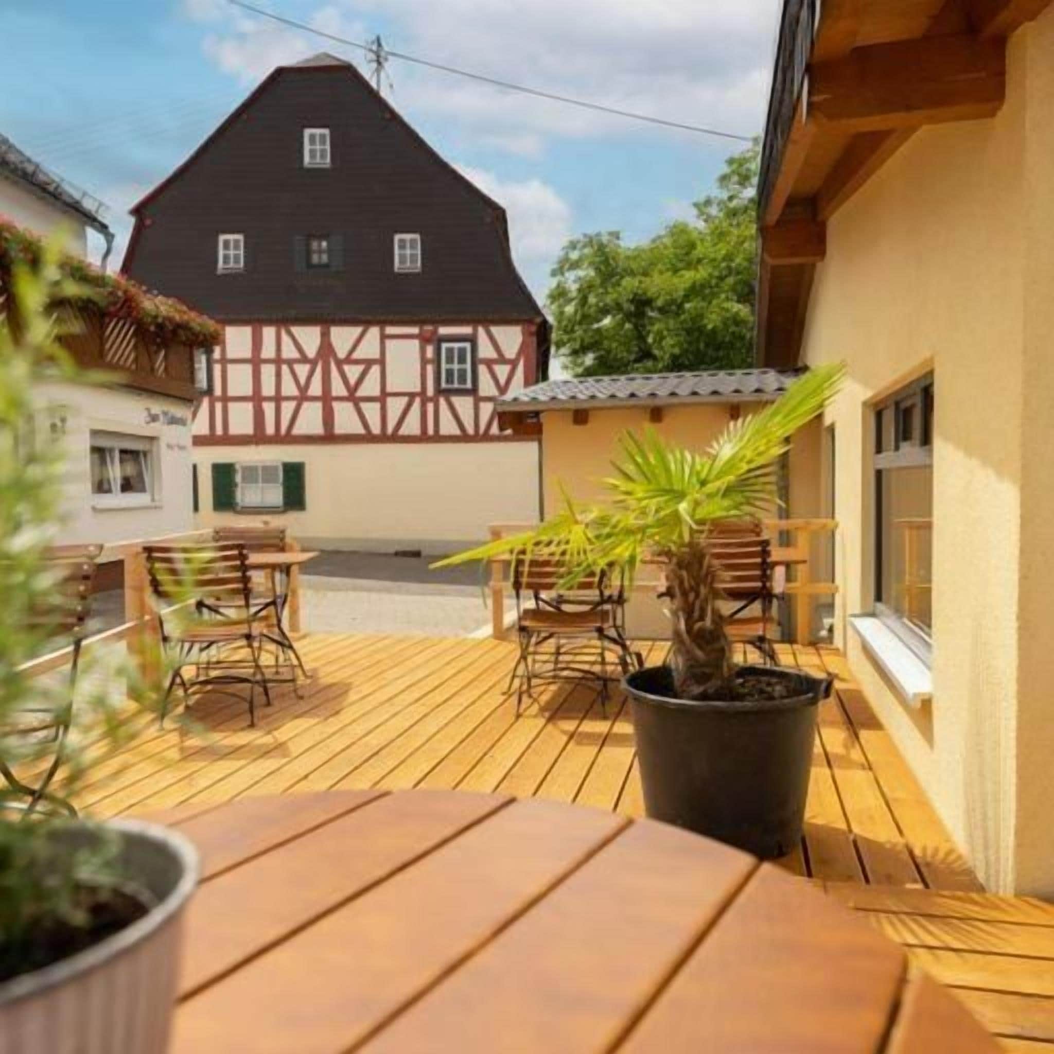 Um deck de madeira com área de estar externa e um vaso com planta.