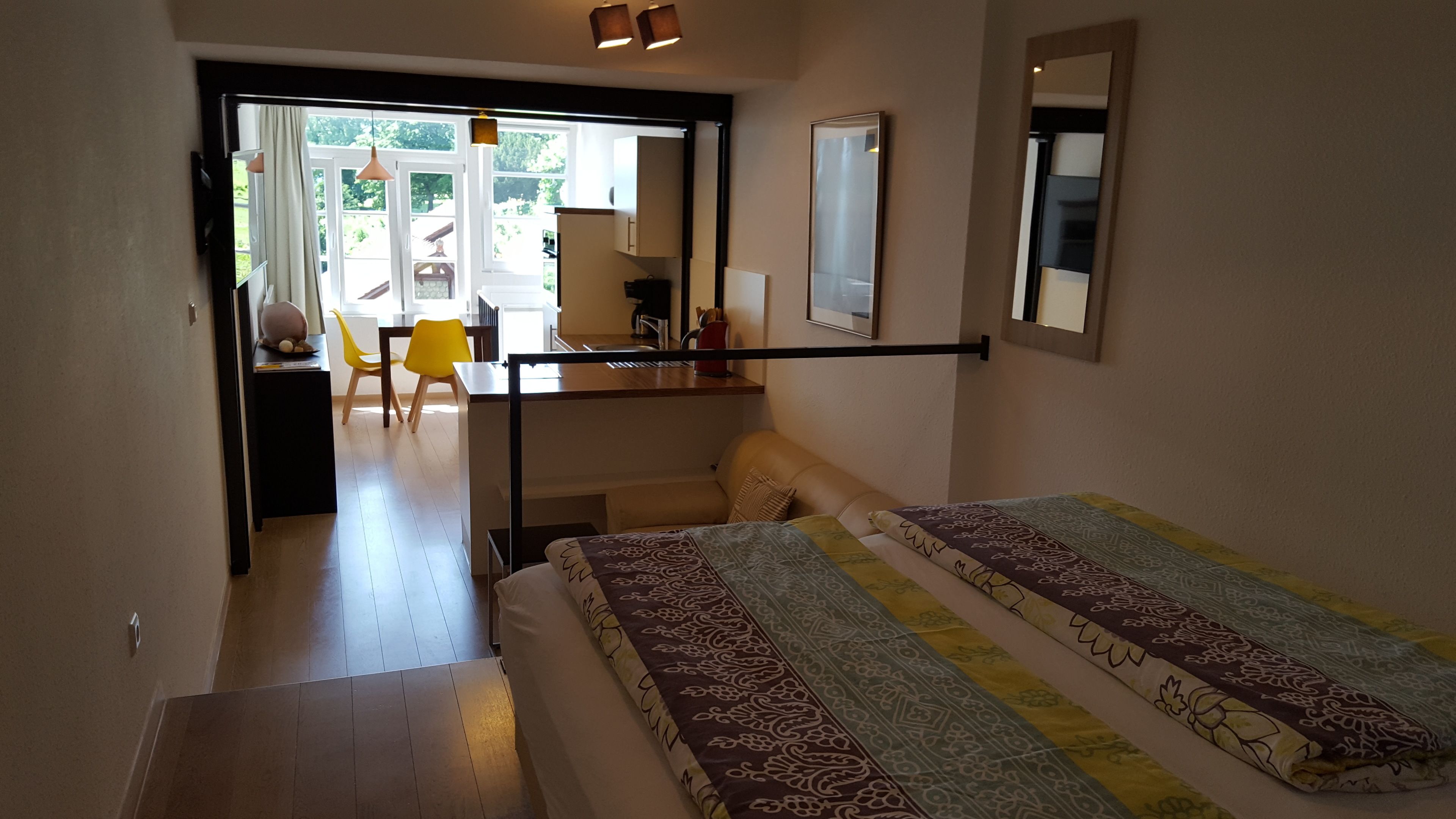 Quarto com cama, escrivaninha e cadeira. Janela com cortinas e vista para o exterior.