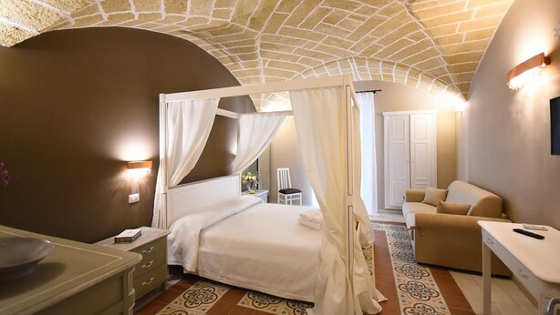 Um quarto com cama, escrivaninha, cadeira e sofá.