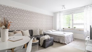Quarto moderno com papel de parede estampado, uma cama, um sofá, uma mesa de jantar e uma televisão.