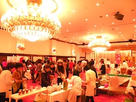 Um evento lotado em ambiente interno, com lustres e mesas.