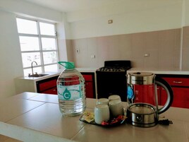 Uma cozinha com um dispensador de água, uma cafeteira e uma chaleira no balcão.