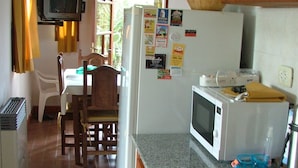 Uma cozinha compacta com micro-ondas, geladeira e uma área de refeições com mesa e cadeiras.